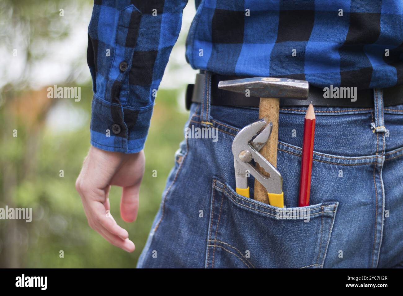 Close up picture of a craftsman with hammer, pencil and gripper in his ...