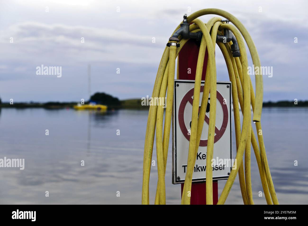 Yellow water hose at a water extraction point Stock Photo - Alamy