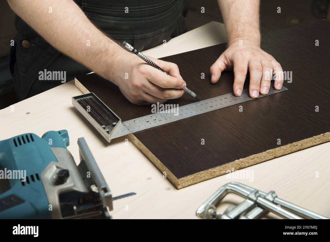Men's hands draw a pencil on the ruler with a sub-standard template for ...