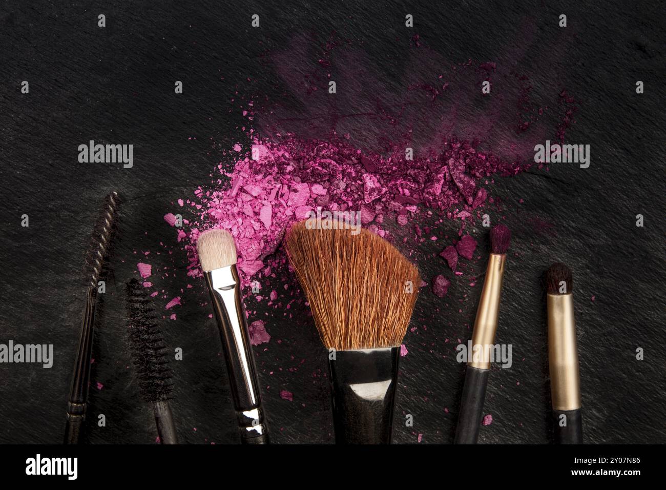 Make-up brushes with crushed cosmetics, shot from above on a black ...