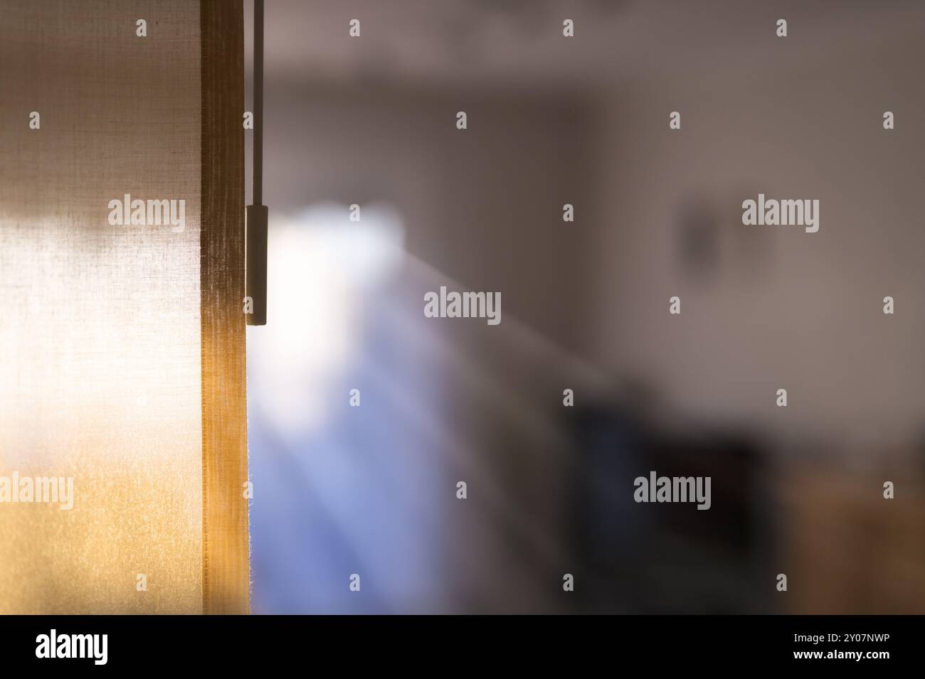 A curtain at the entrance to the living area backlit by the sunlight ...