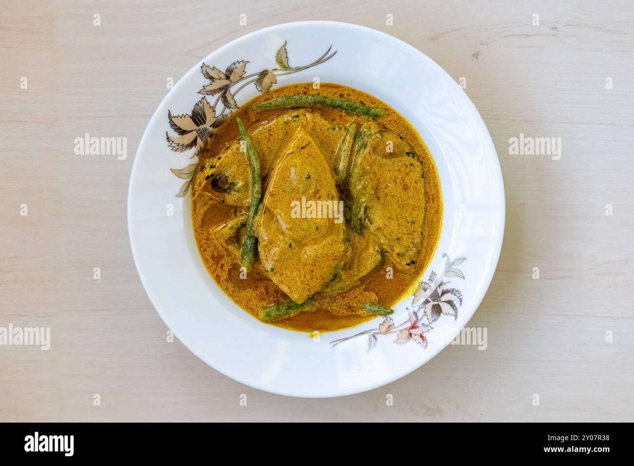 Traditional Bengali cuisine Shorshe Ilish on a white plate, cooked with ...