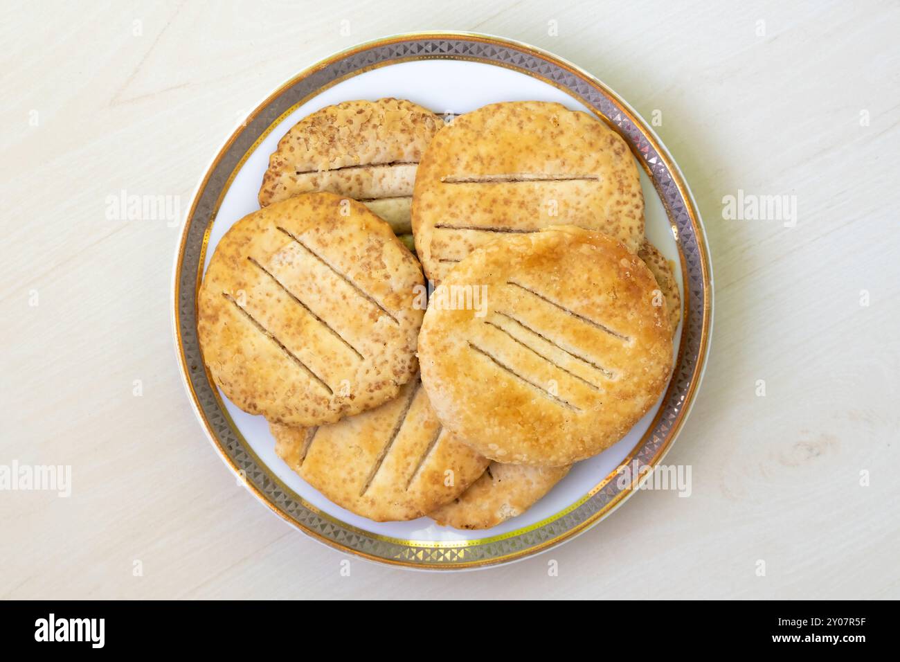 Crispy Bakarkhani on a white plate on wooden background. Baqarkhani is ...