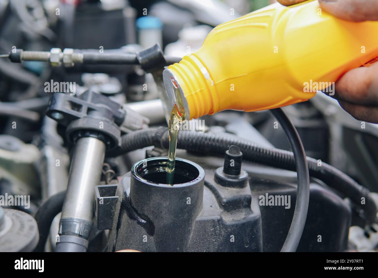 A man is pouring oil into a car engine. Concept of maintenance and care ...