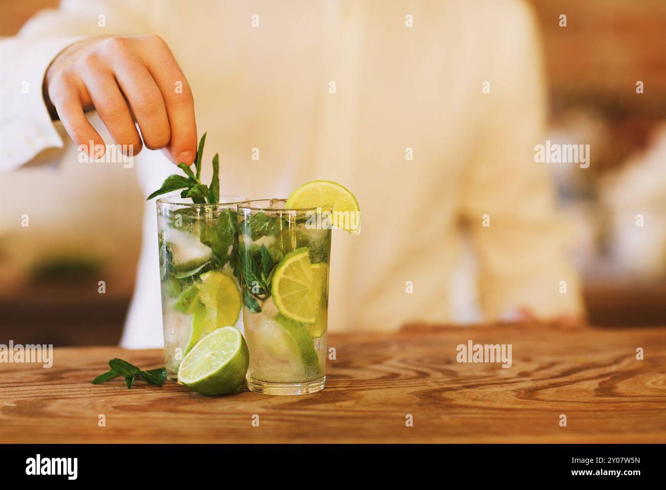 Bartender making two mojito cocktails on wooden bar counter Stock Photo - Alamy