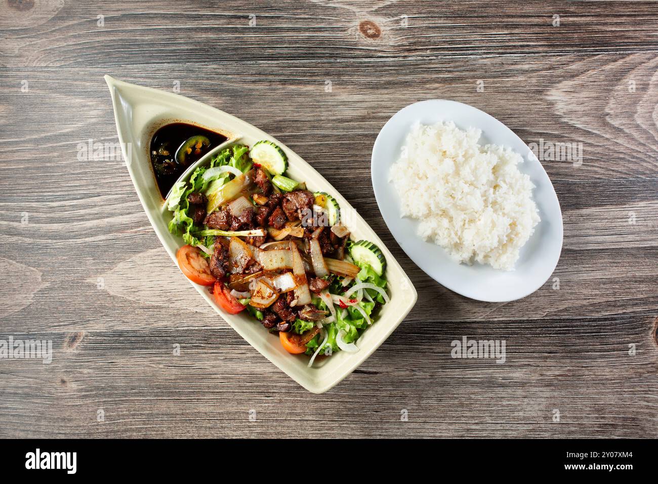 A top down view of a platter of shaking beef, with steamed white rice ...