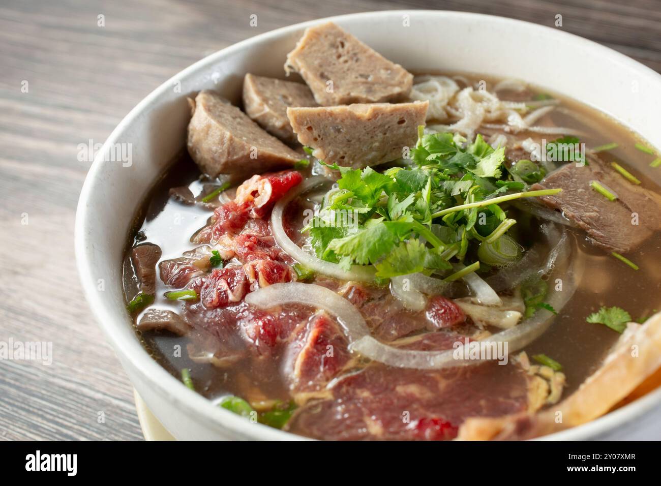 A view of a bowl of pho, featuring rare steak, flank, tendon, and tripe ...