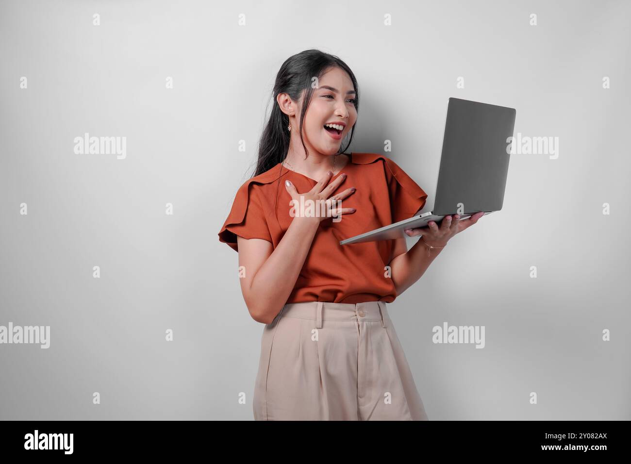 Happy mindful thankful young Asian woman smiling while holding laptop ...