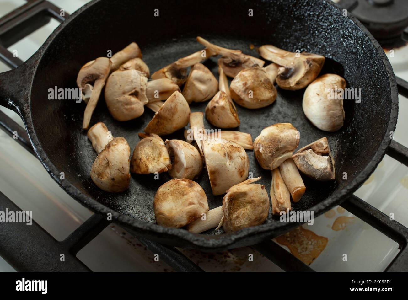 A view of a quartered button mushrooms sauteing in a cast iron skillet ...
