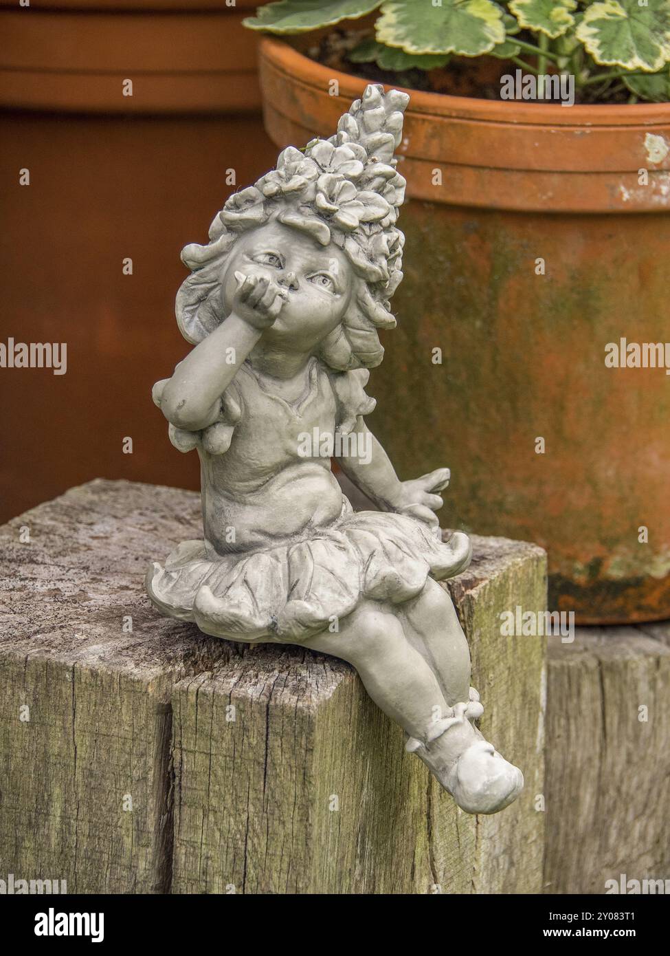 Stone sculpture of a sitting child on a blunt wooden block, in the ...