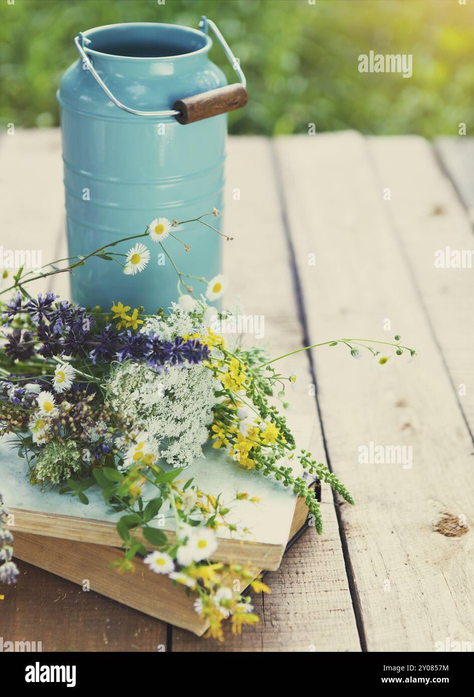 Still life with flowers near watering can with old books on a rustic ...