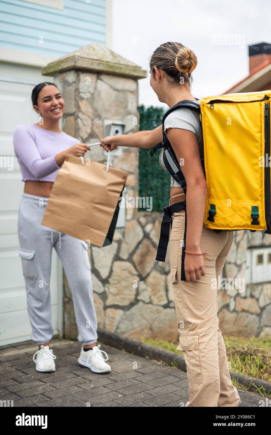 vertical female food delivery worker, seen from behind, hands over a ...