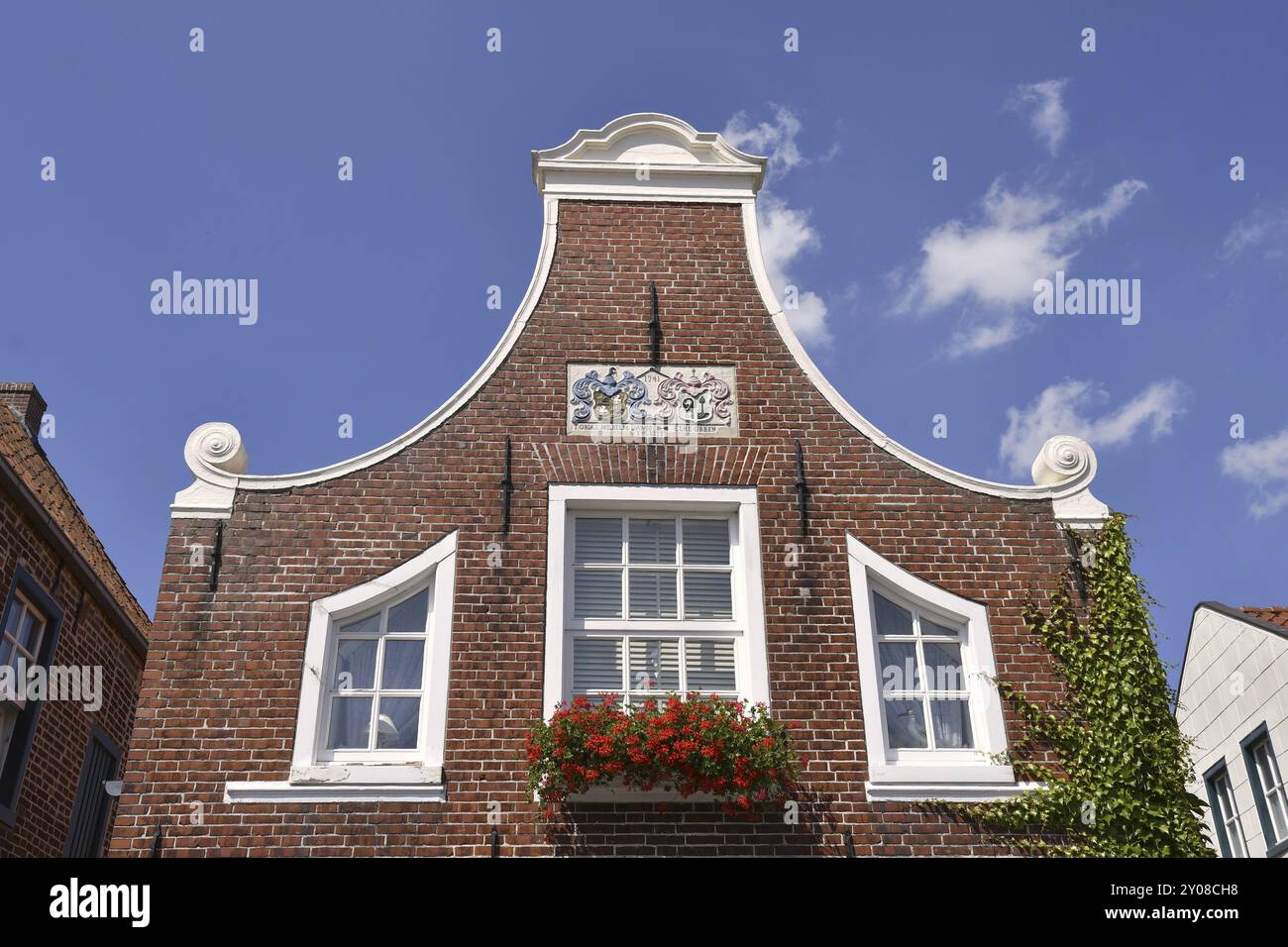 Detail of a historic brick house with stepped gable and flowers under a ...