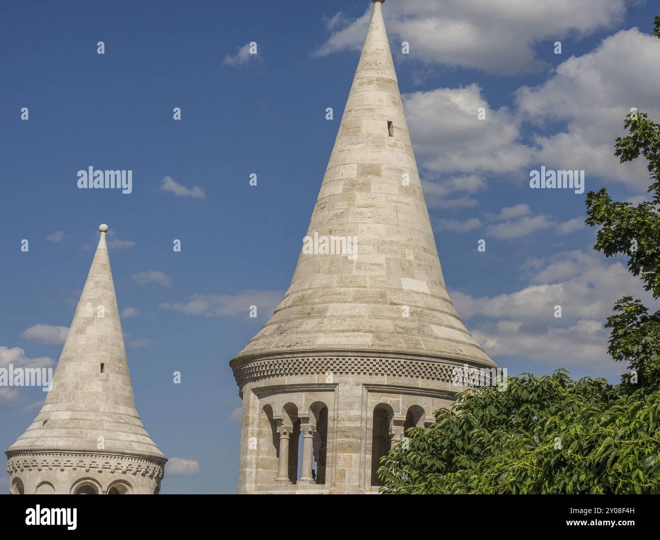 Two historic stone towers under a clear blue sky with clouds, budapest ...