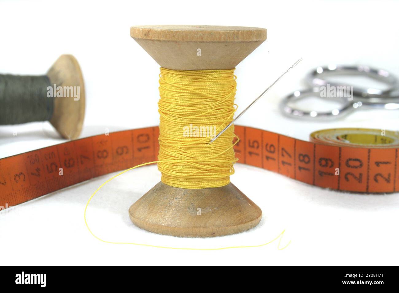 Old spool of thread with needle, tape measure and scissors on a white ...