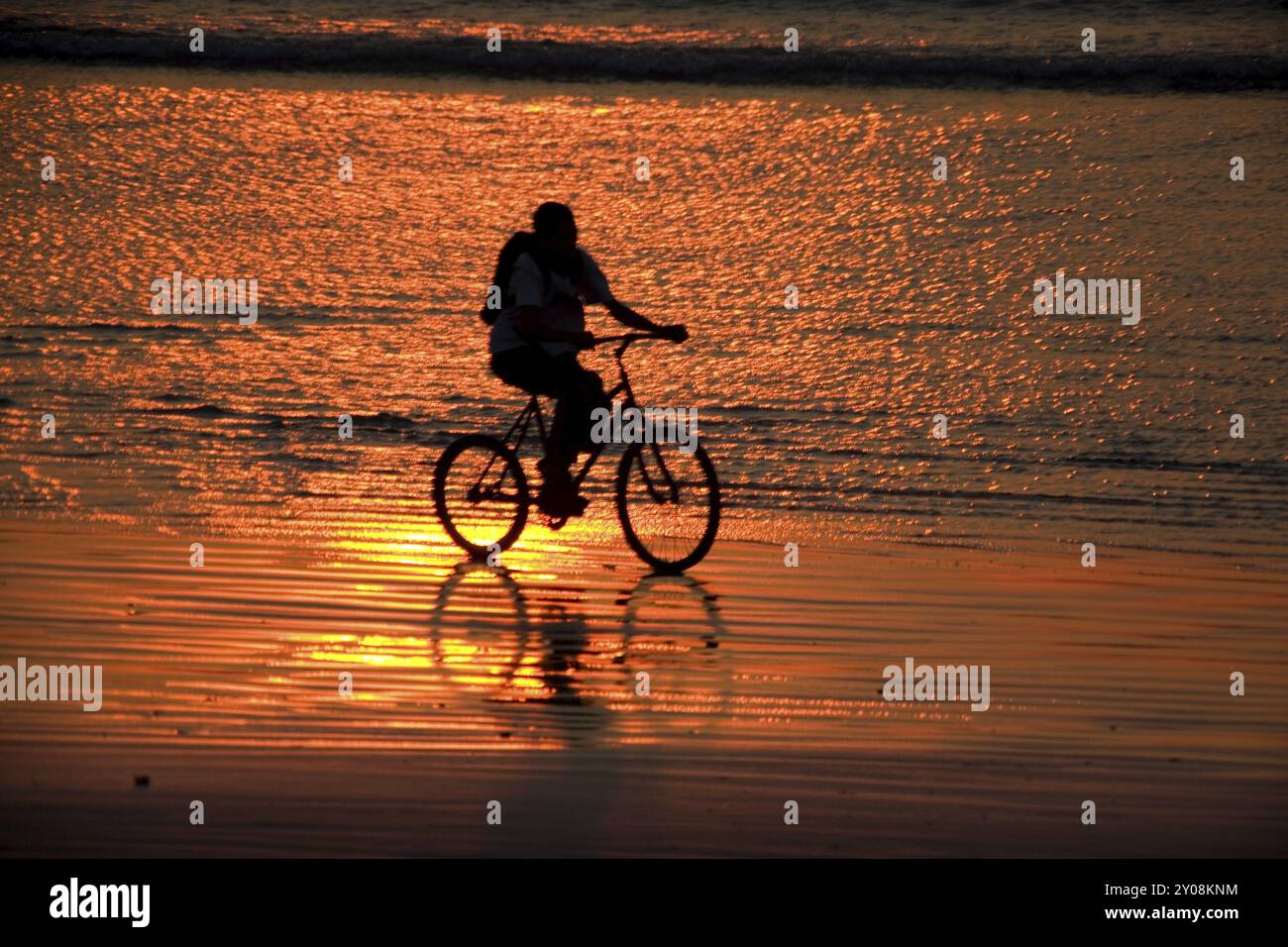 Cyclist at sunset on the beach Stock Photo - Alamy