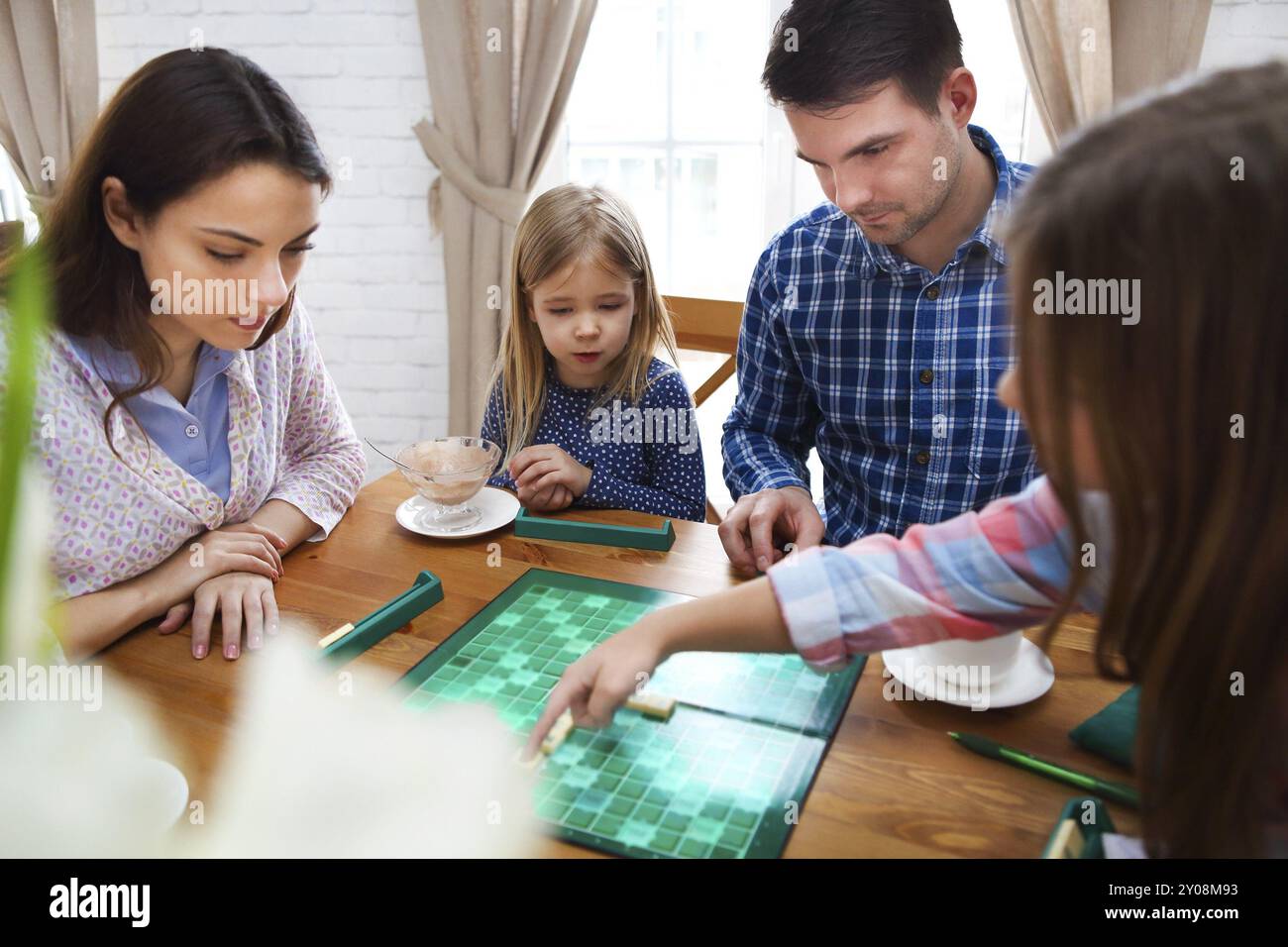 Happy young family plaing board game with two daughters Stock Photo - Alamy