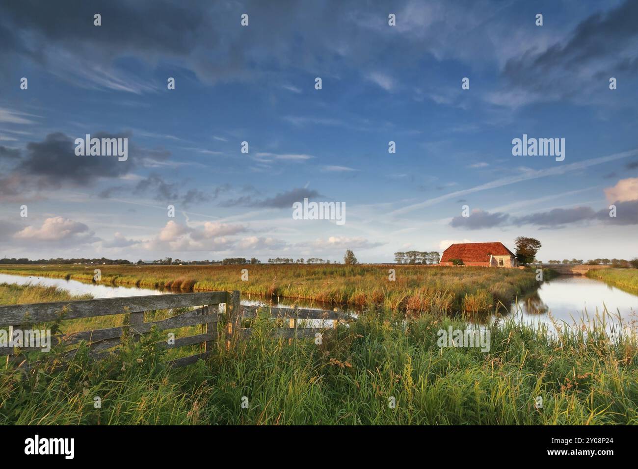 Gold sunshine over farmhouse by river Stock Photo - Alamy