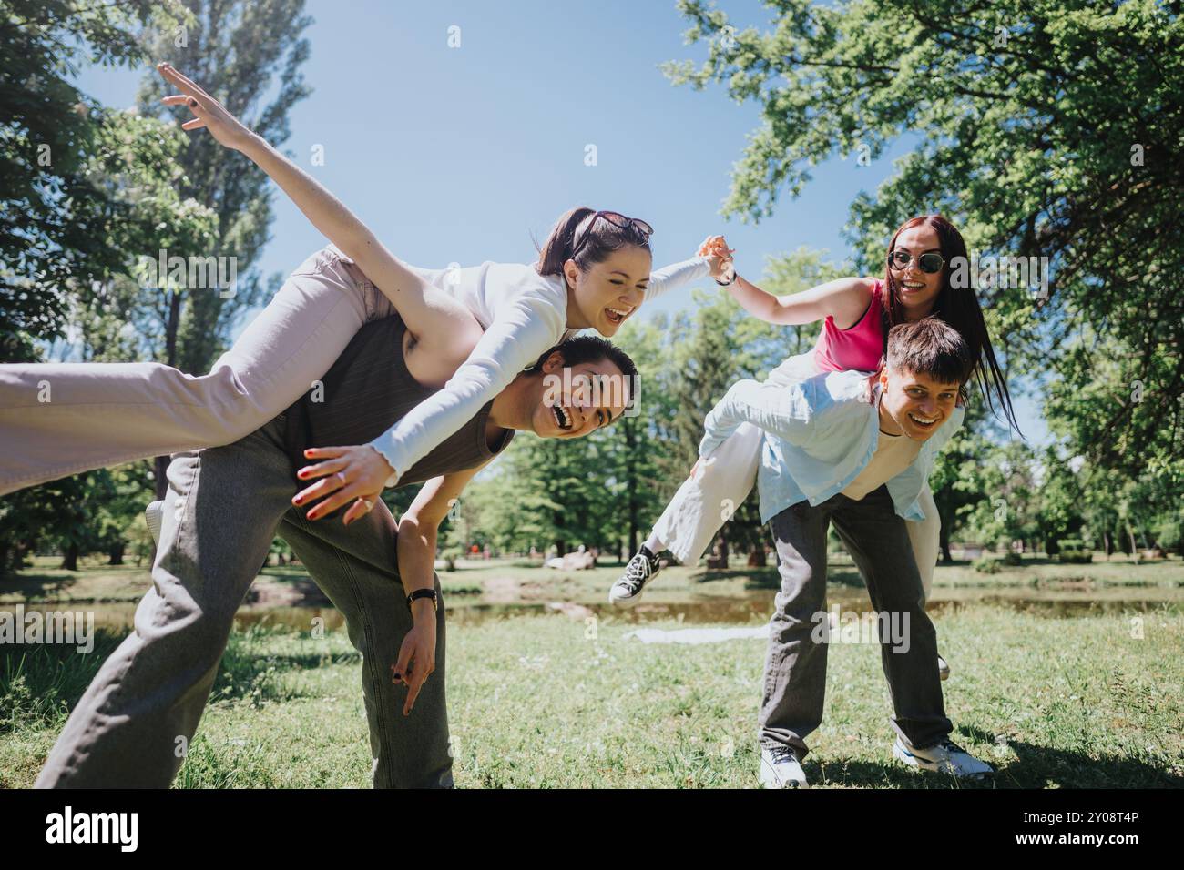 Happy friends enjoying a fun piggyback ride in a sunny park Stock Photo ...