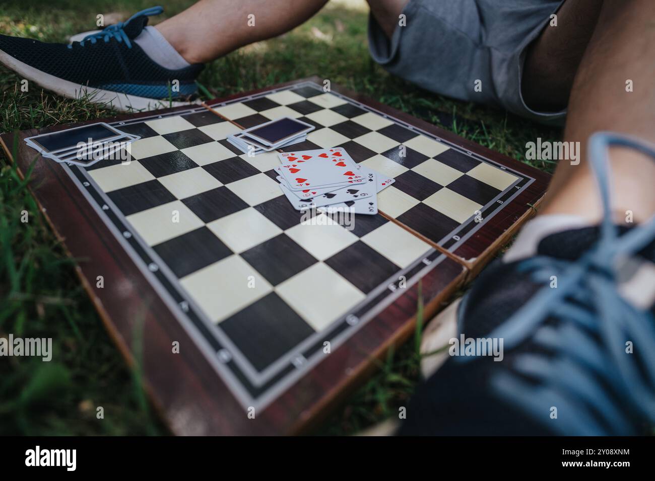 Outdoor game setup with chessboard and playing cards on grass Stock ...