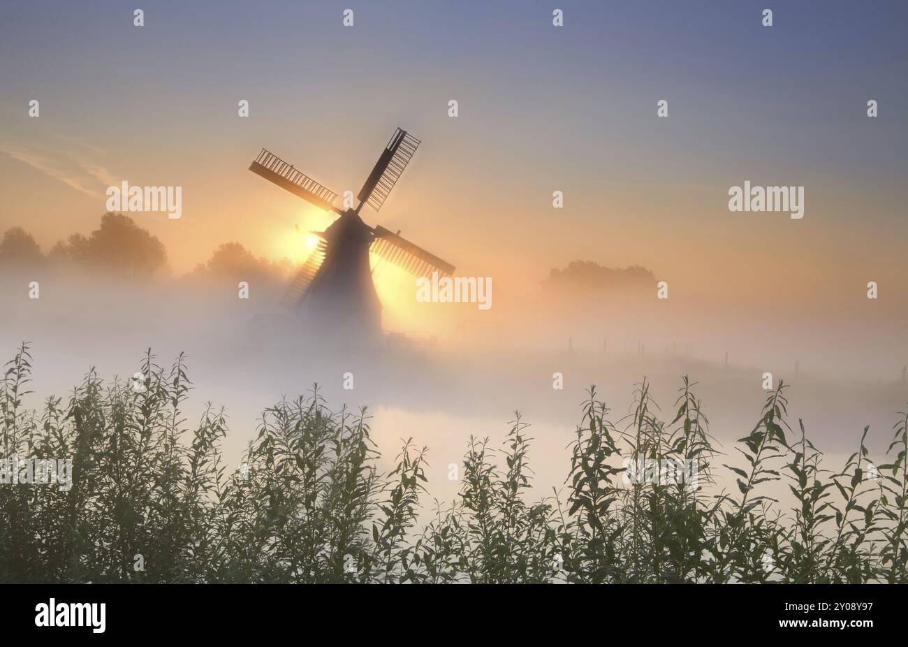 Misty sunrisebehind the windmill near river Stock Photo - Alamy