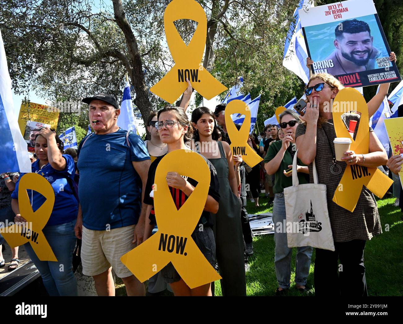 People hold cut outs of yellow ribbons at a protest calling for a ...