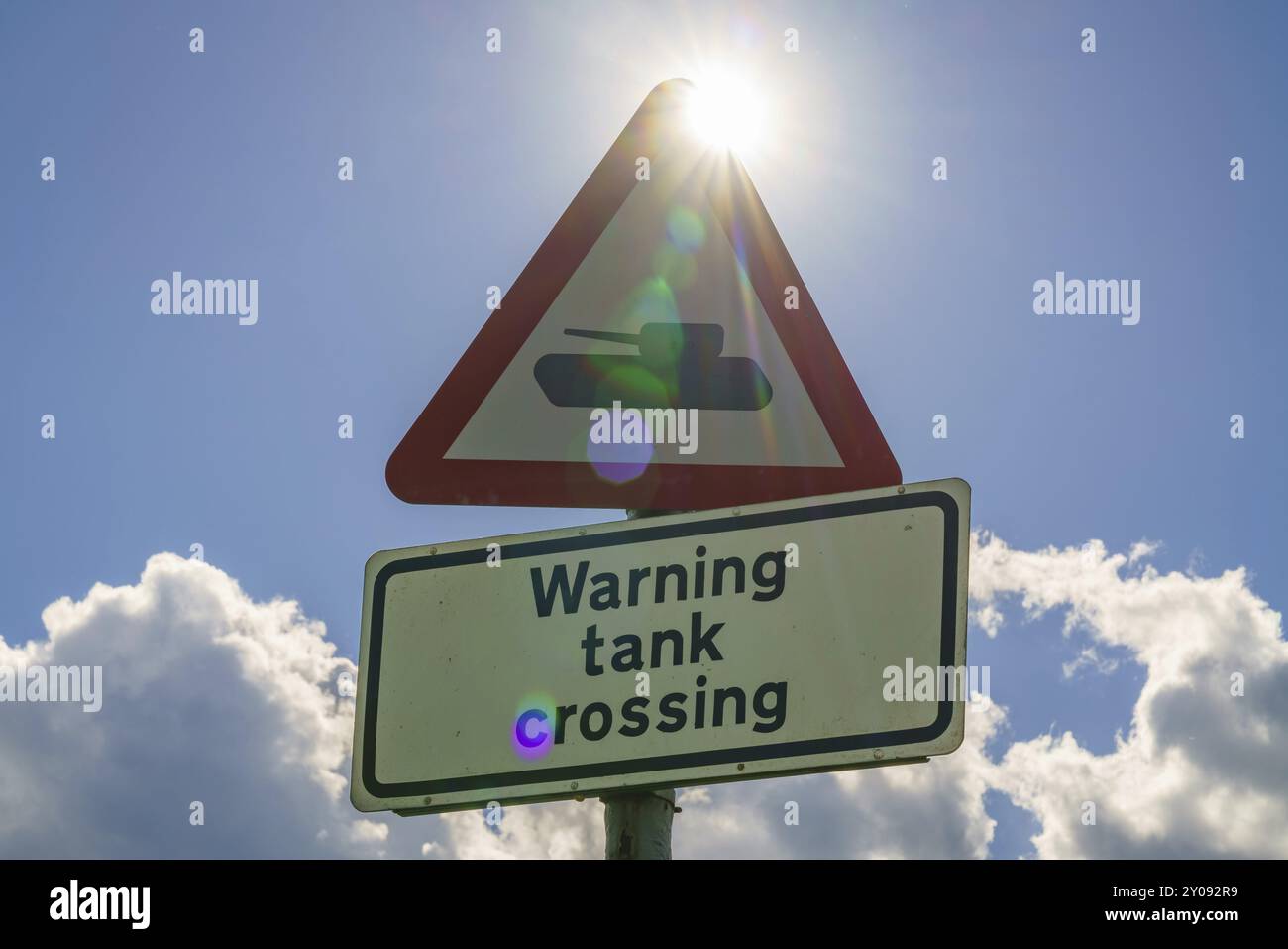 Sign: Warning, tank crossing with a sunstar and some clouds, seen near ...