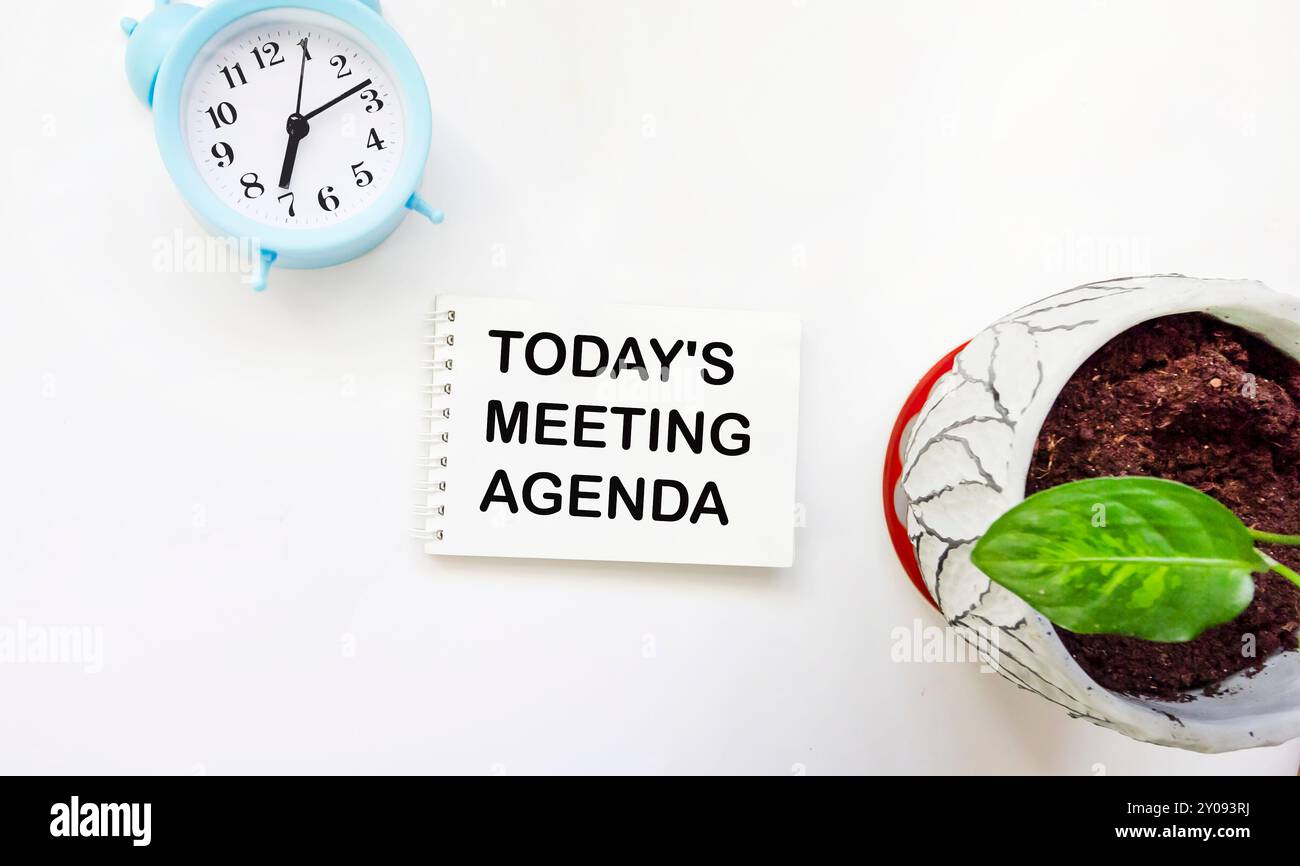 The text of today's meeting agenda is written on a notepad on a white ...