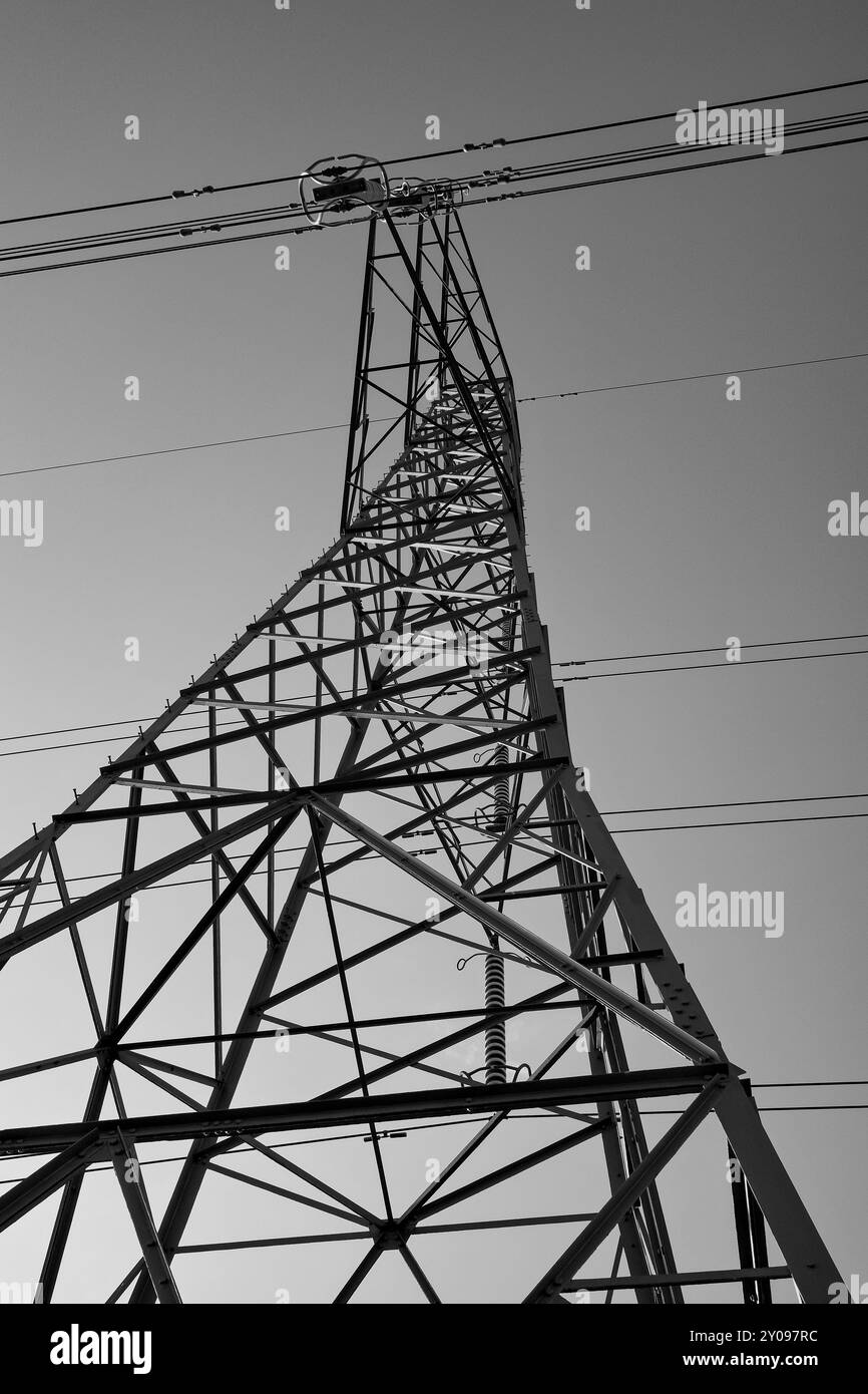 Black and white close-up of a towering power line structure against a ...
