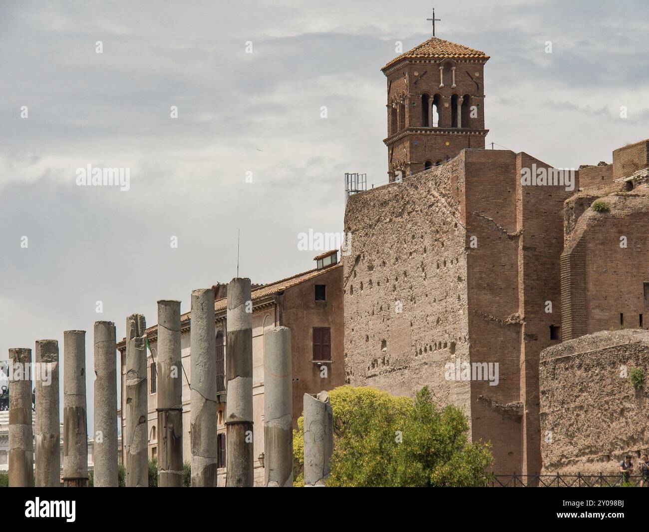Roman ruins with ancient columns and a brick tower in the background ...