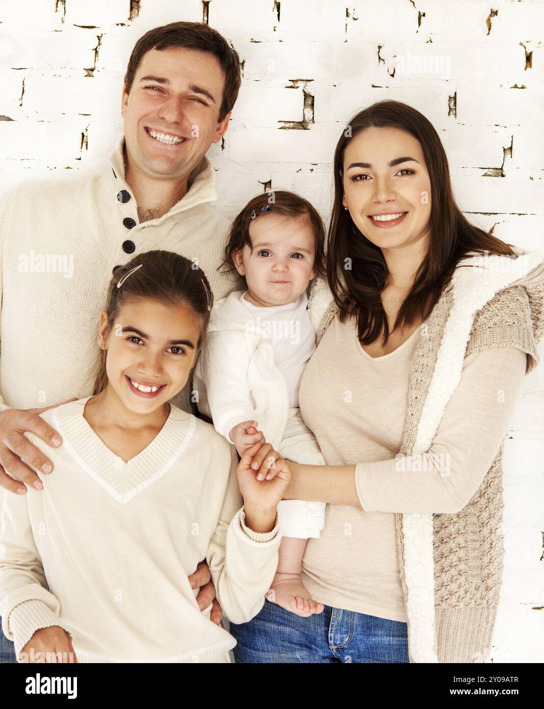 Portrait of a happy smiling family near white brick wall Stock Photo ...