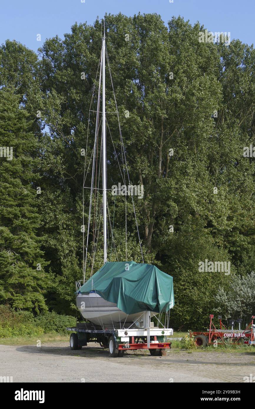 Shrink wrapped sail boat on trailer, stored away for winter in front of ...