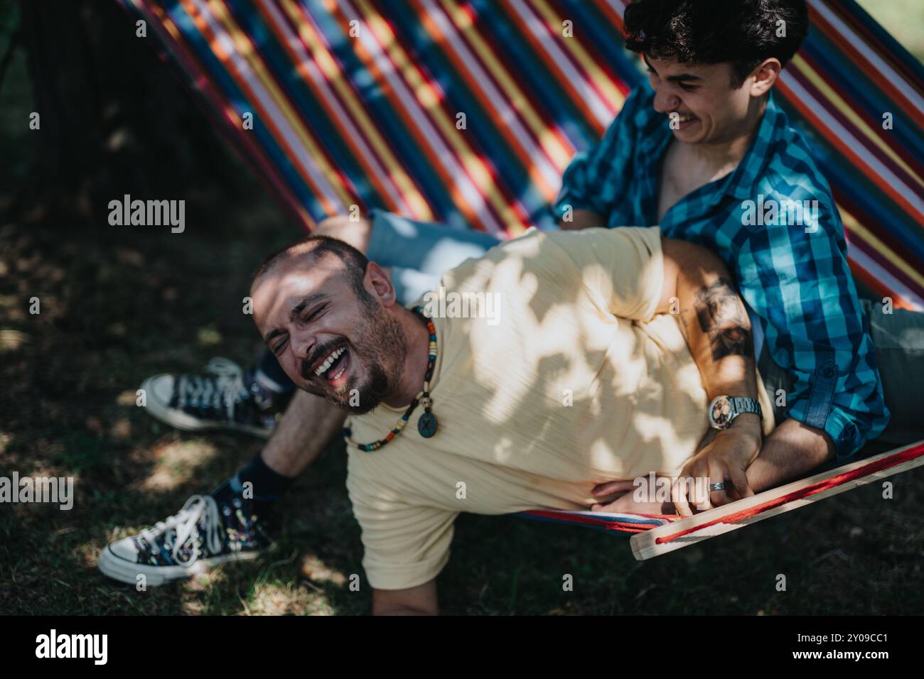 Two friends laughing and relaxing together on a colorful hammock ...
