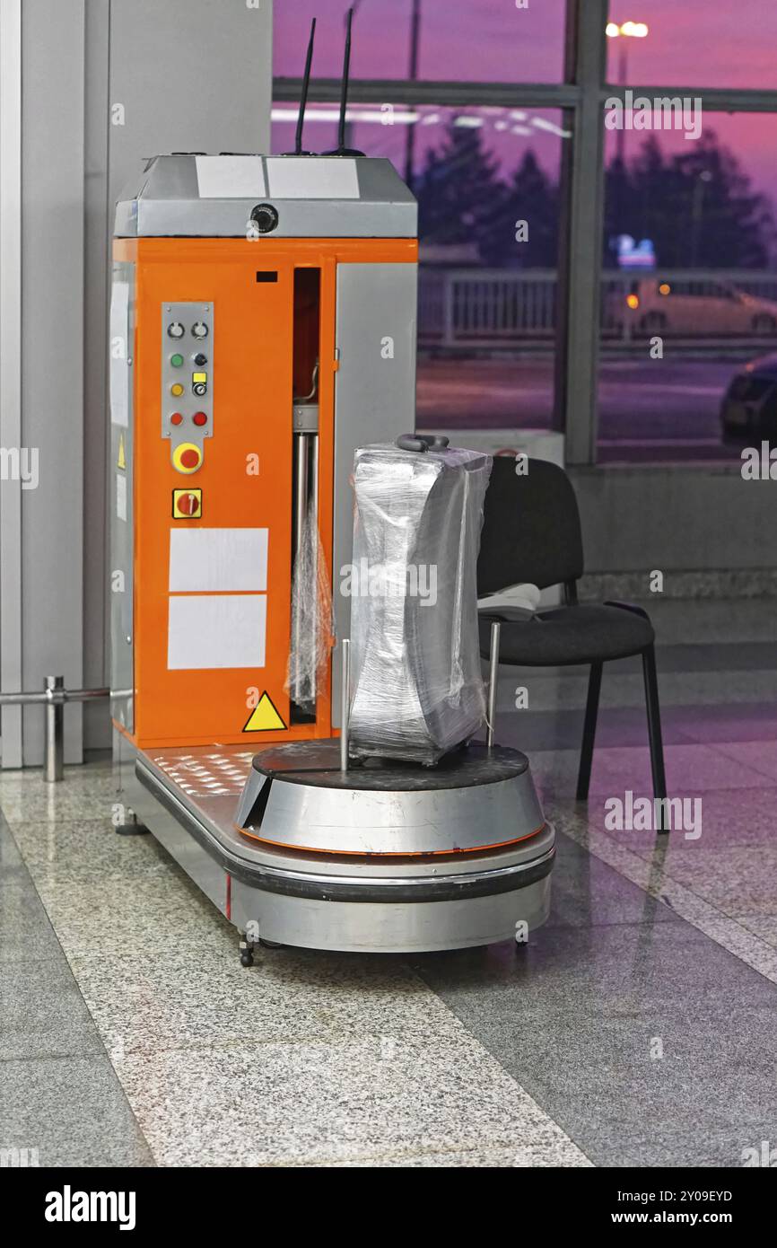 Plastic wrap luggage machine at airport Stock Photo - Alamy