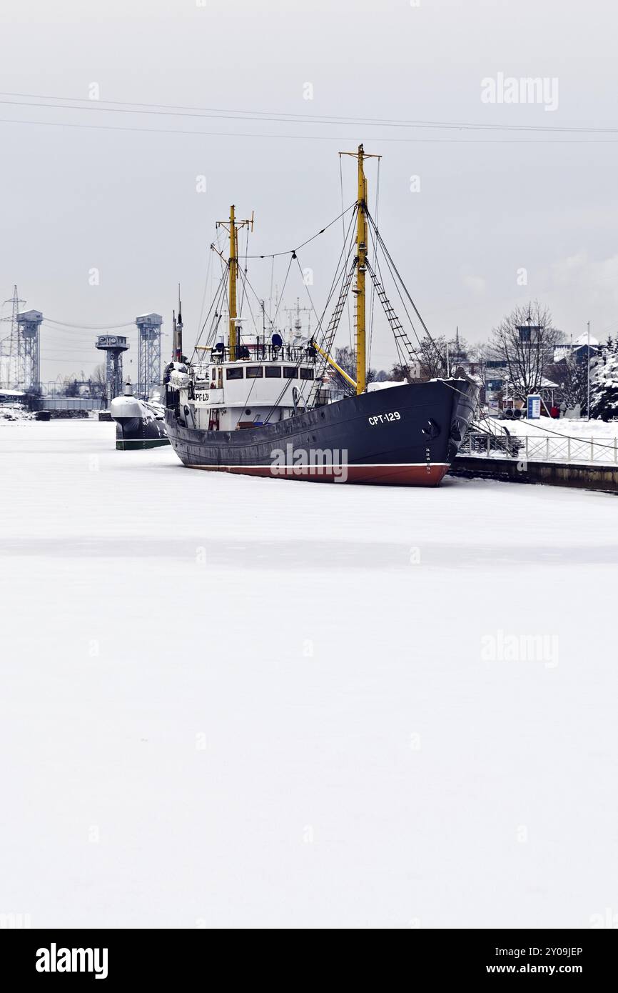 Average fishing trawler, bound with ice. Embankment of Peter the Great ...