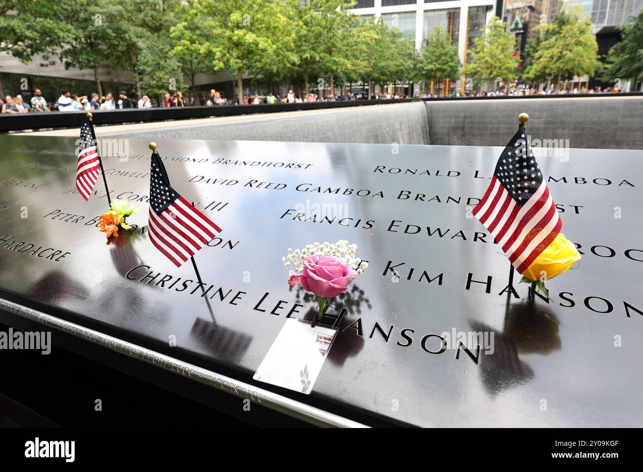 Flowers and flags with photos are placed on the name panels at the ...