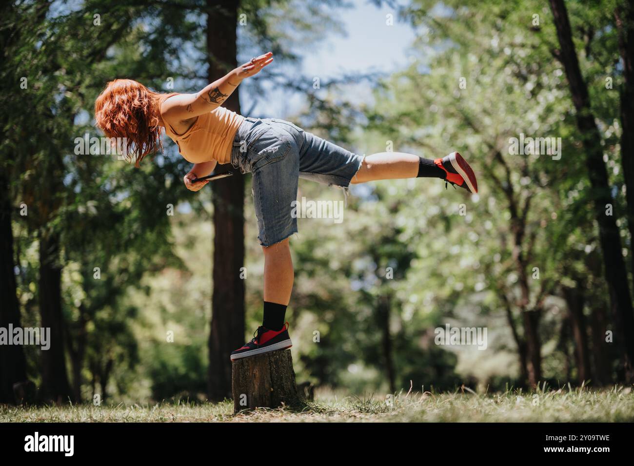 Woman balancing on a tree stump in nature, achieving equilibrium Stock ...