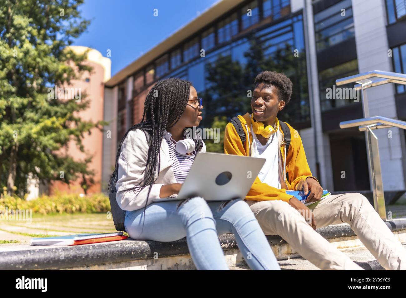 Two african american students using laptop sitting on the campus Stock ...