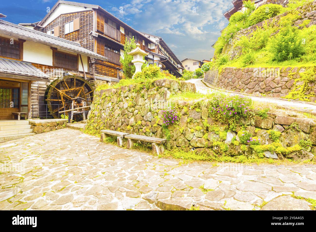Traditional wooden houses and waterwheel line the stone path on this ...