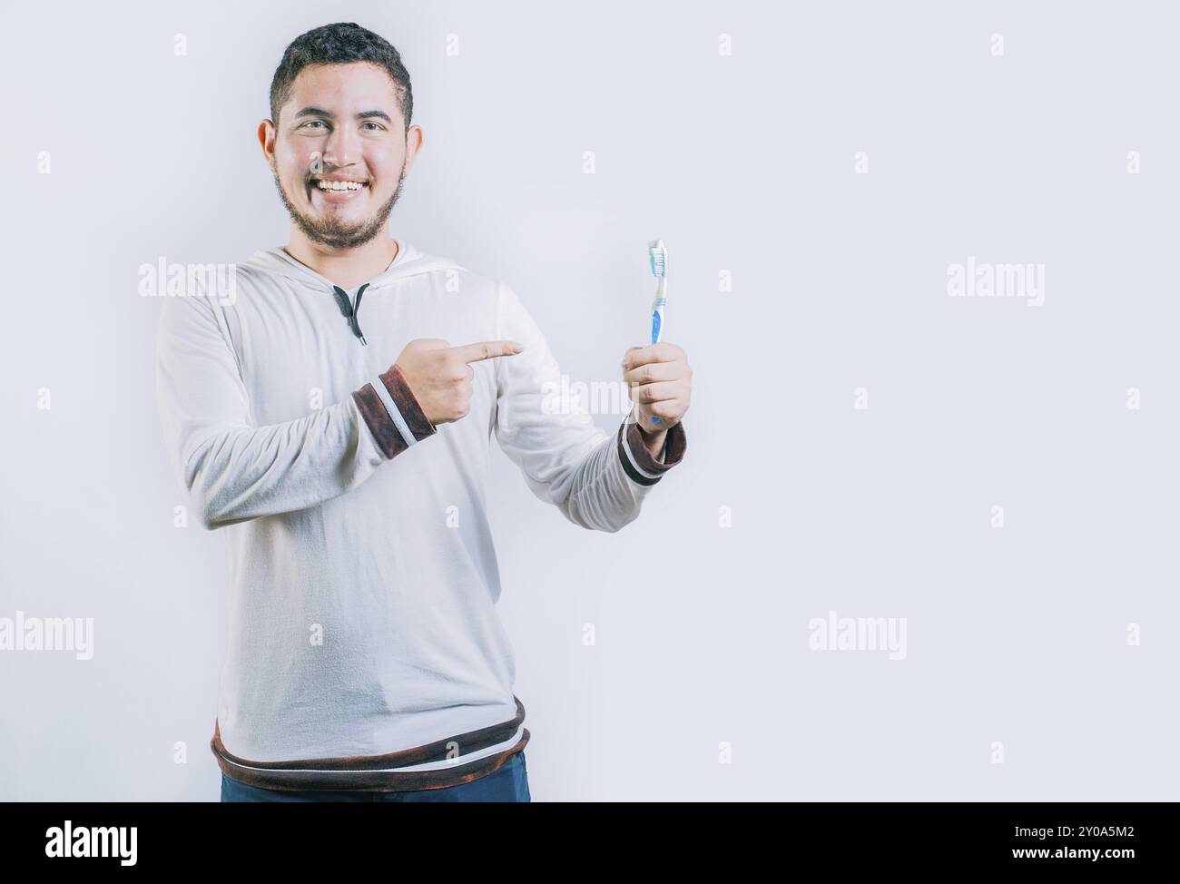 Happy guy pointing at toothbrush isolated. Handsome man holding and ...