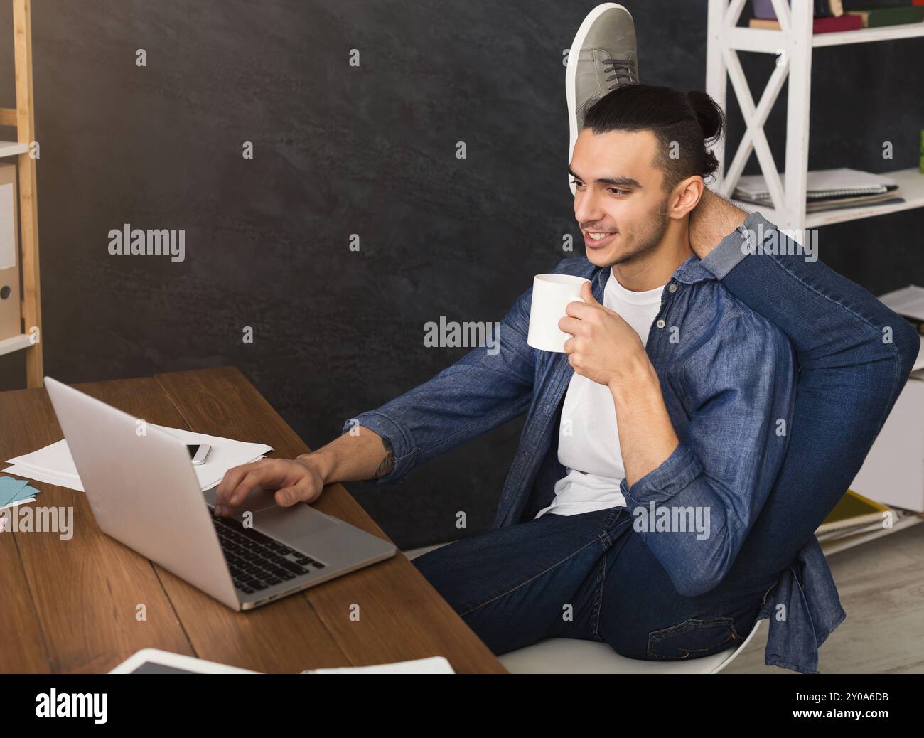Flexible man practicing yoga at workplace Stock Photo - Alamy