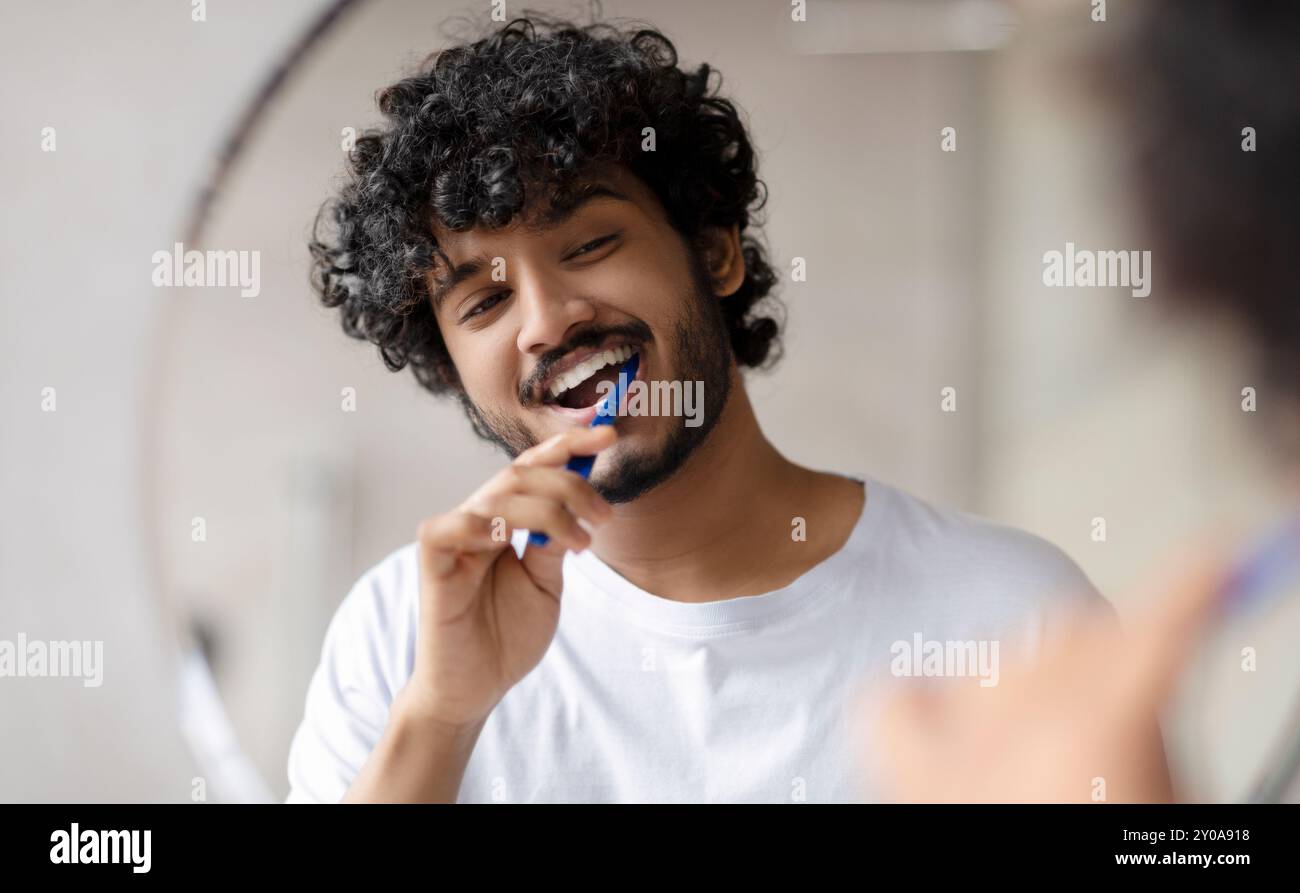 Oral care concept. Young indian man cleaning teeth with toothbrush ...