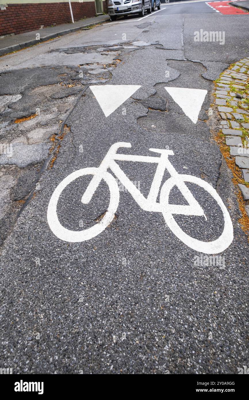 A cycle path pictogram on a road with potholes in Moenchengladbach ...