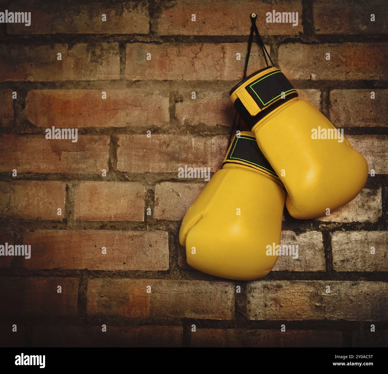 Pair of yellow boxing gloves hanging on a brick wall Stock Photo - Alamy