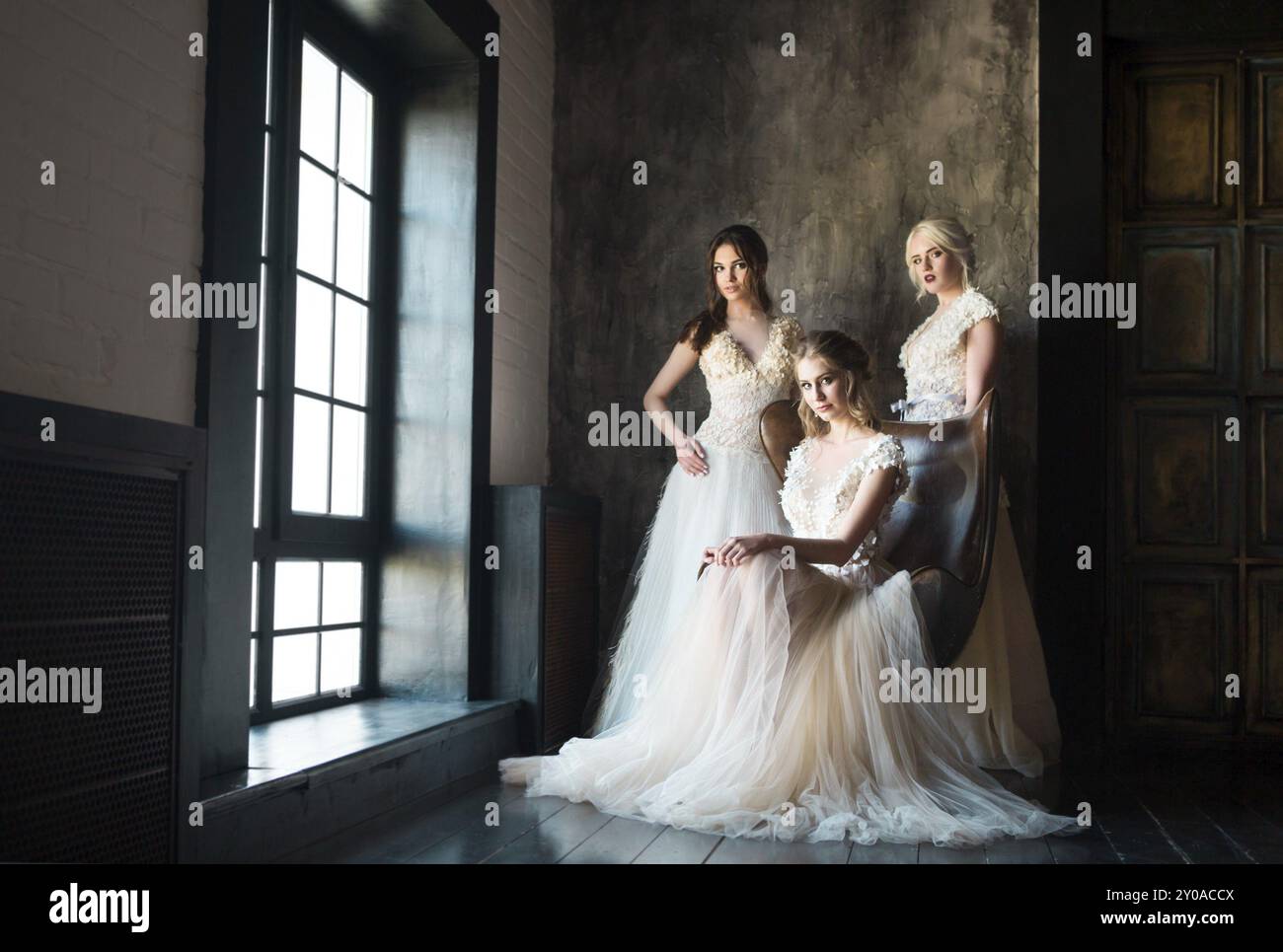 Three young women near window wearing wedding dresses Stock Photo - Alamy