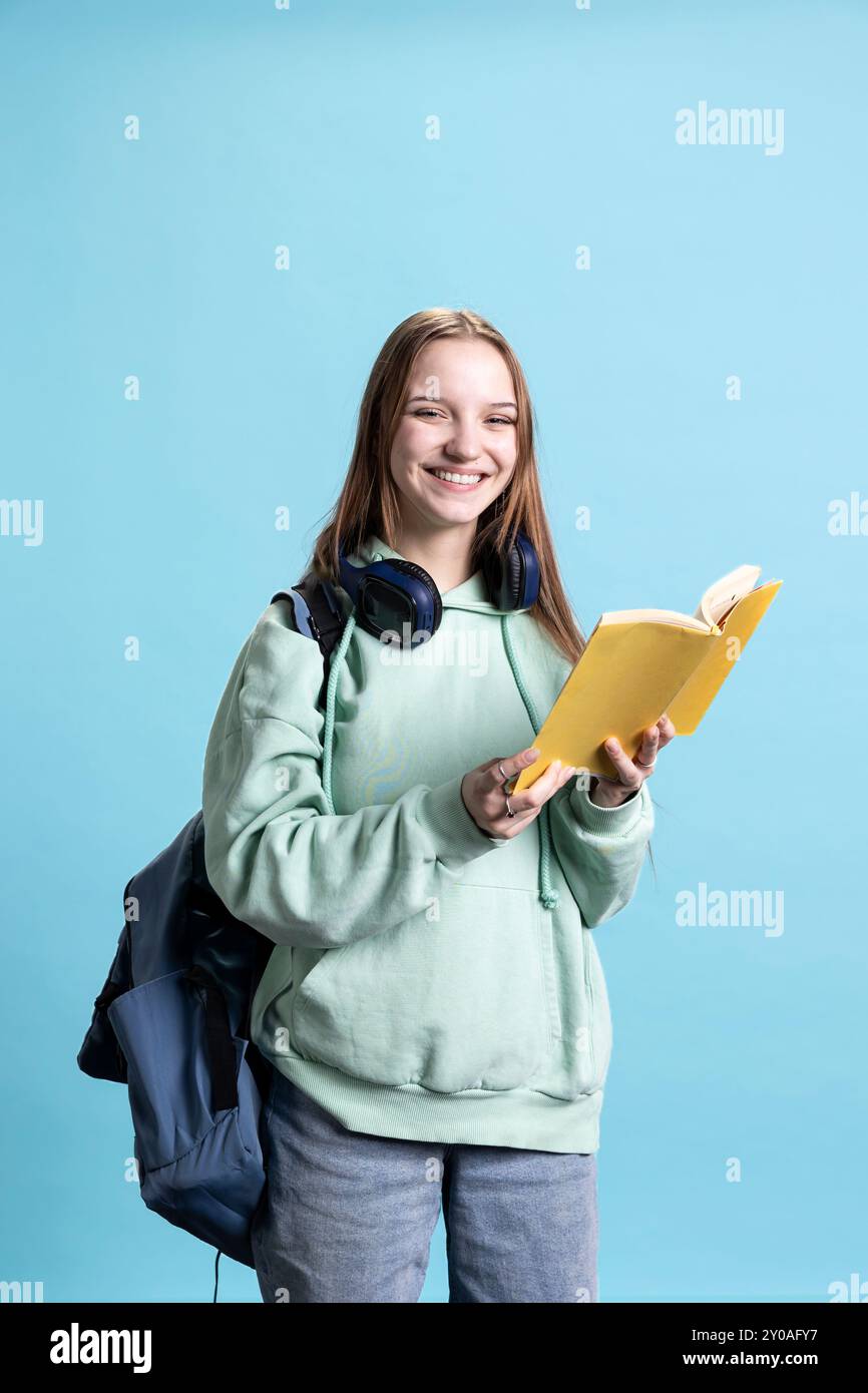 Portrait of happy young girl smiling while reading book, enjoying hobby ...