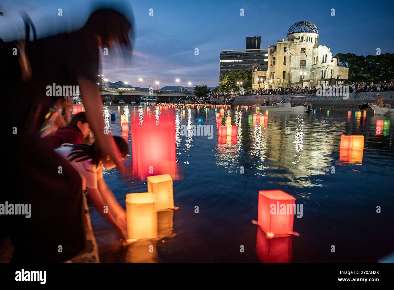 Woman and girl float lanterns on the river, in front of Atomic Bomb ...