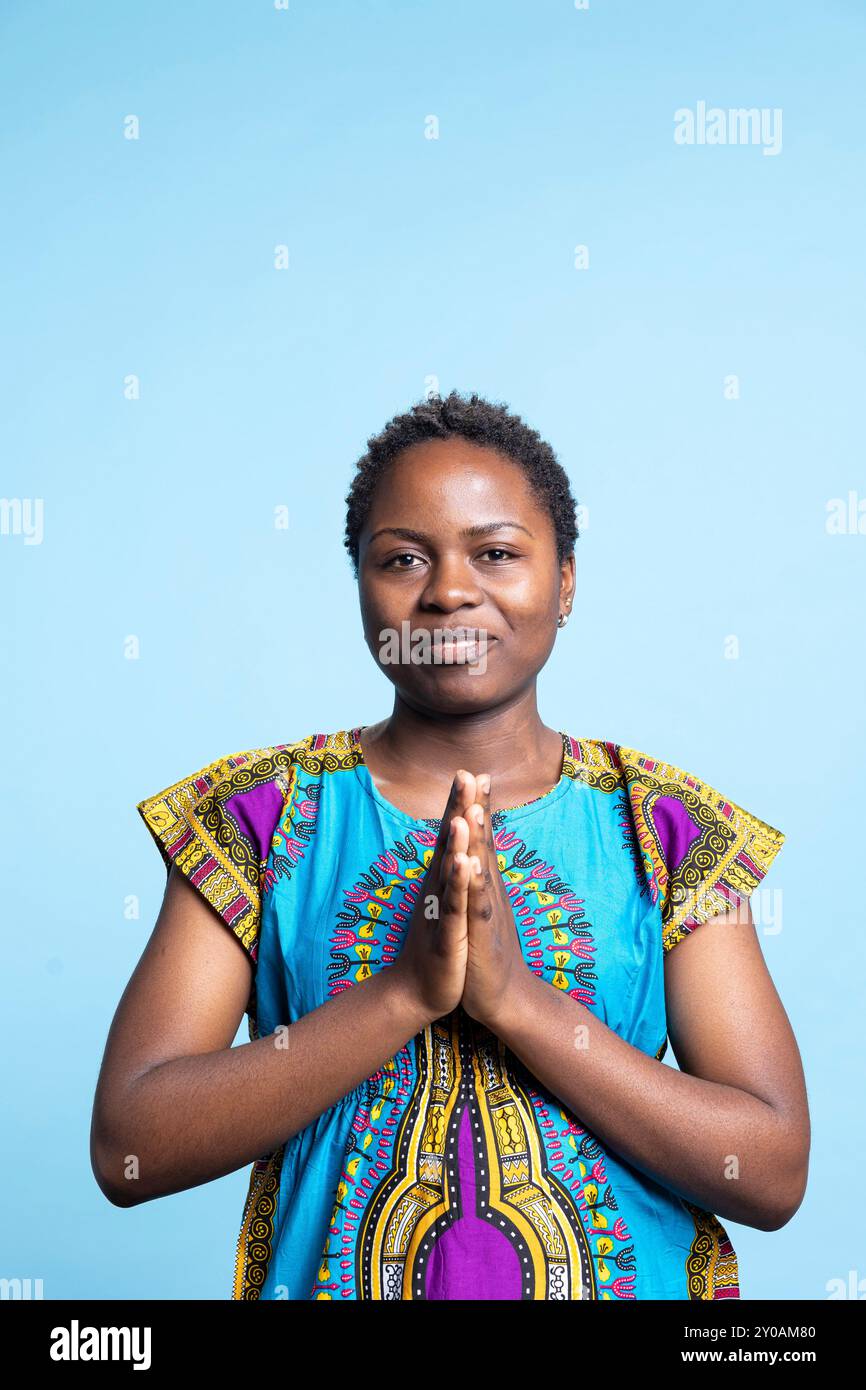 Wearing customary ethnic attire, african american woman worshipping and ...