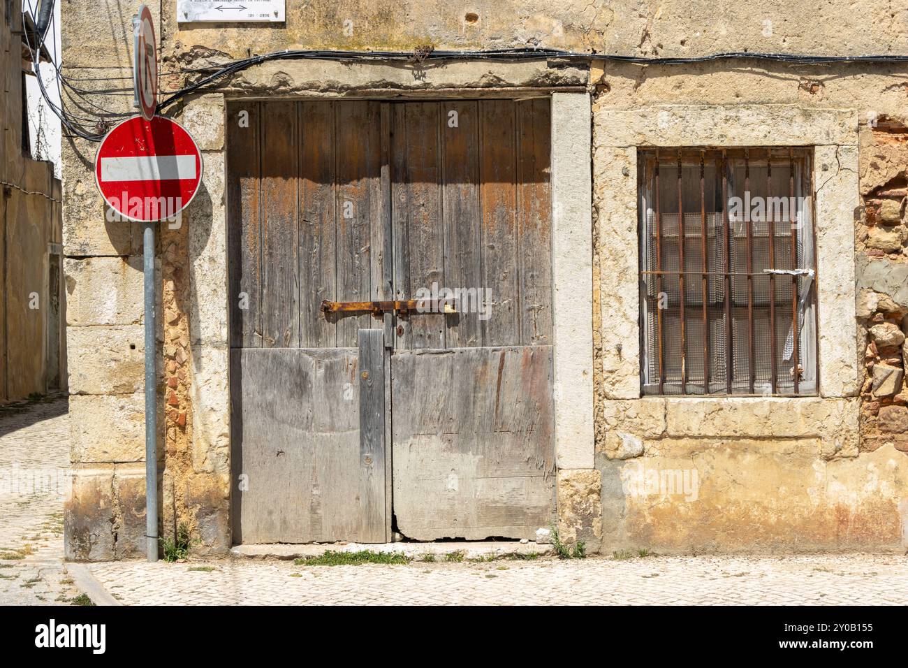 Old weathered wooden door with a rusty lock and a barred window are set ...