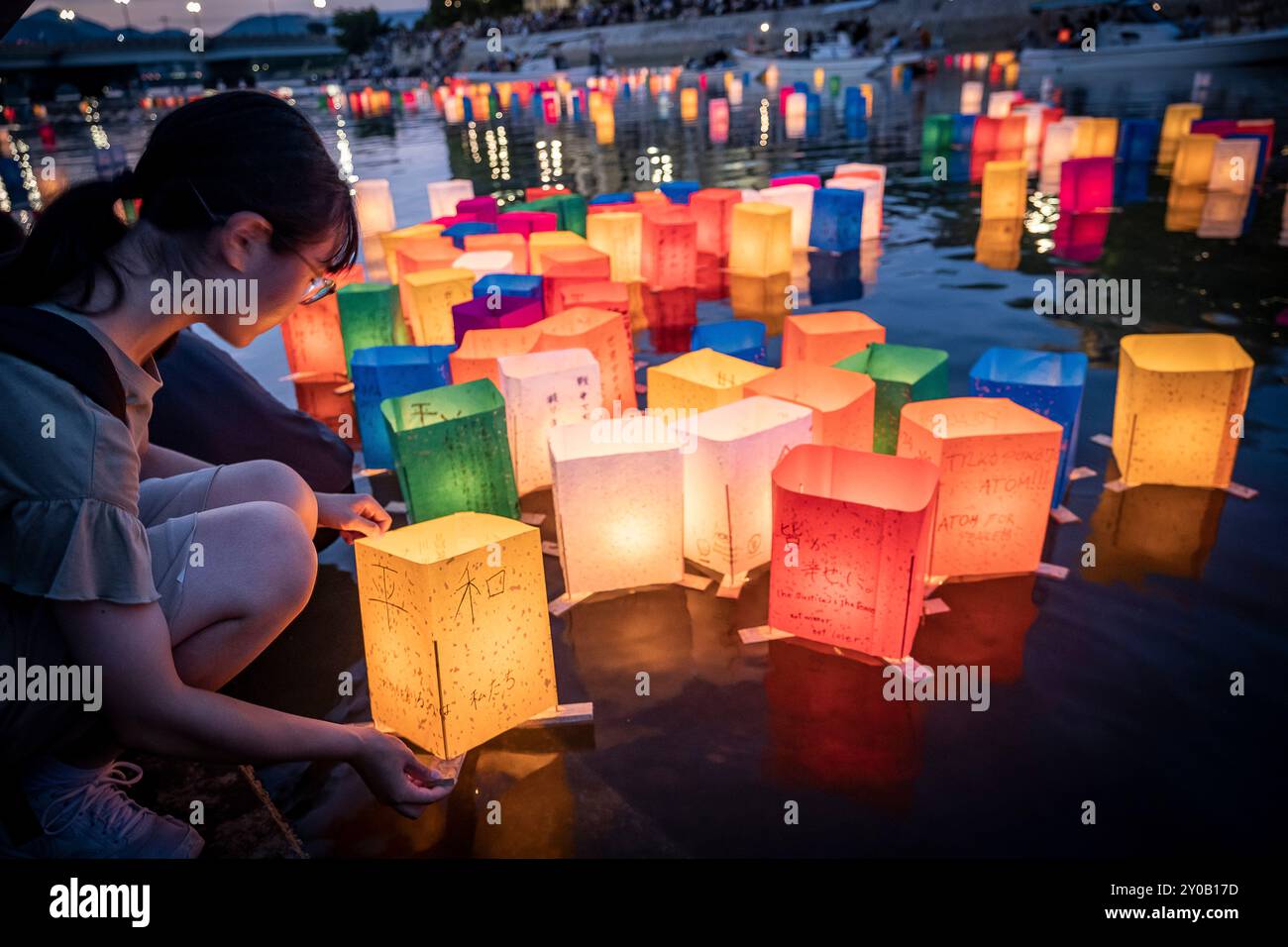 Woman float lanterns on the river, in front of Atomic Bomb Dome with ...